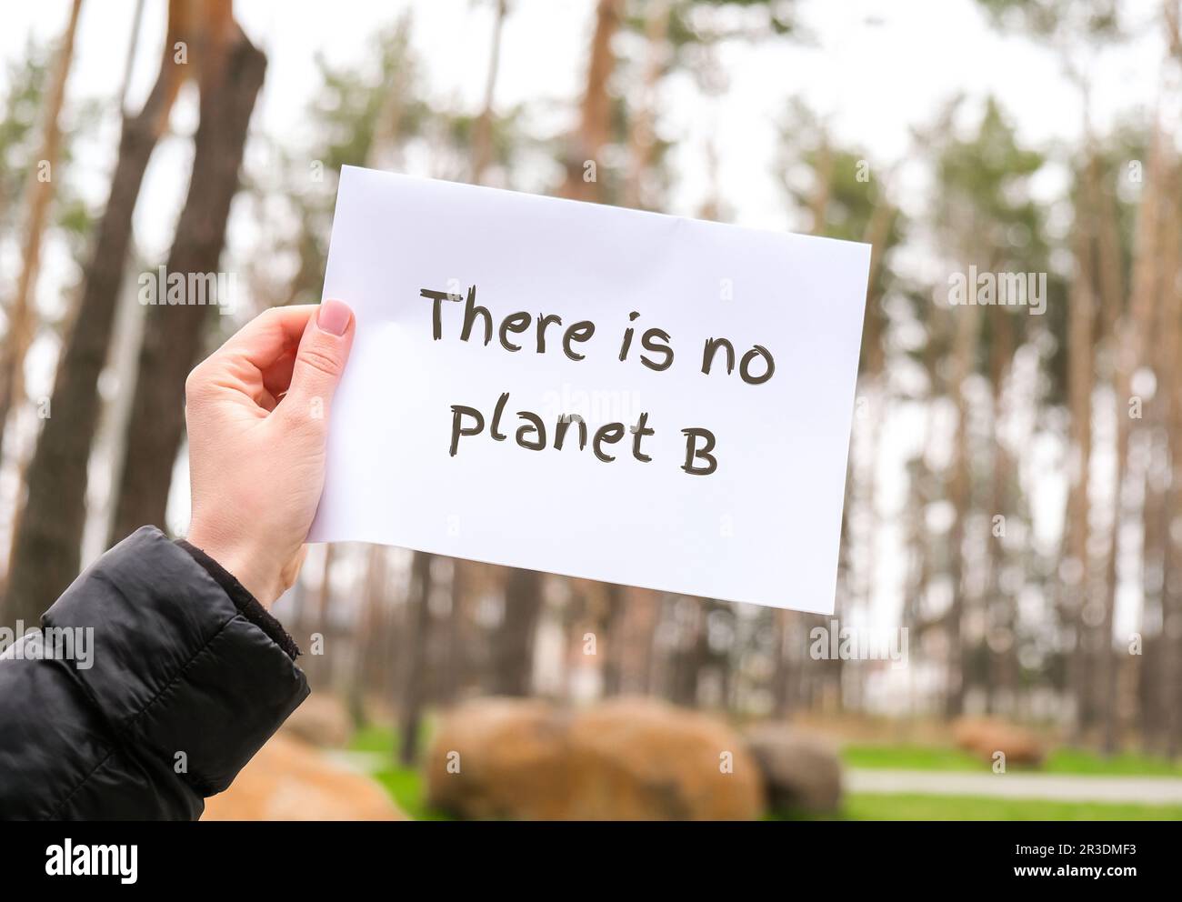 Female hands holding white paper sheet with text THERE IS NO PLANET B ...