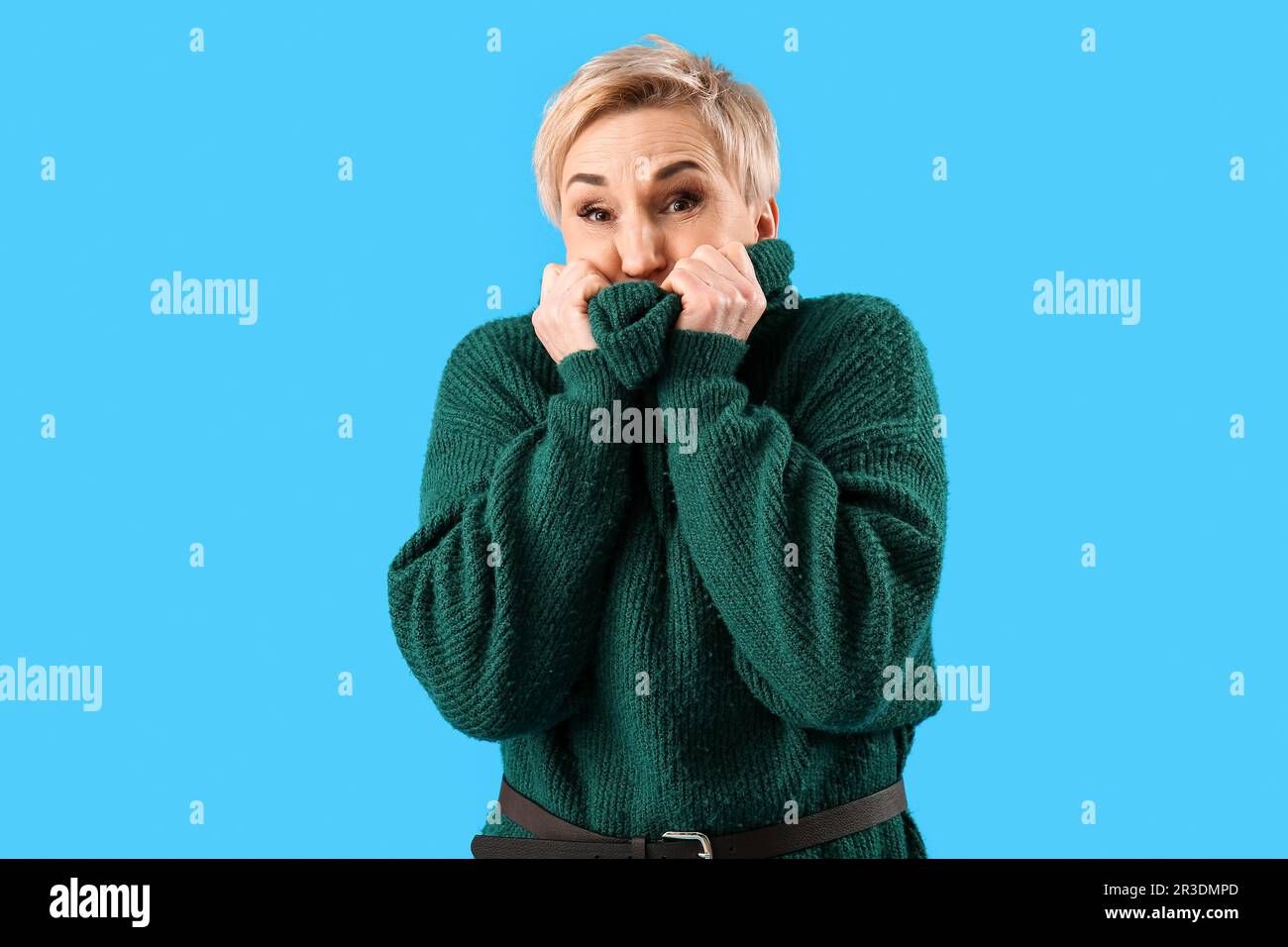 Scared mature woman on light blue background Stock Photo - Alamy