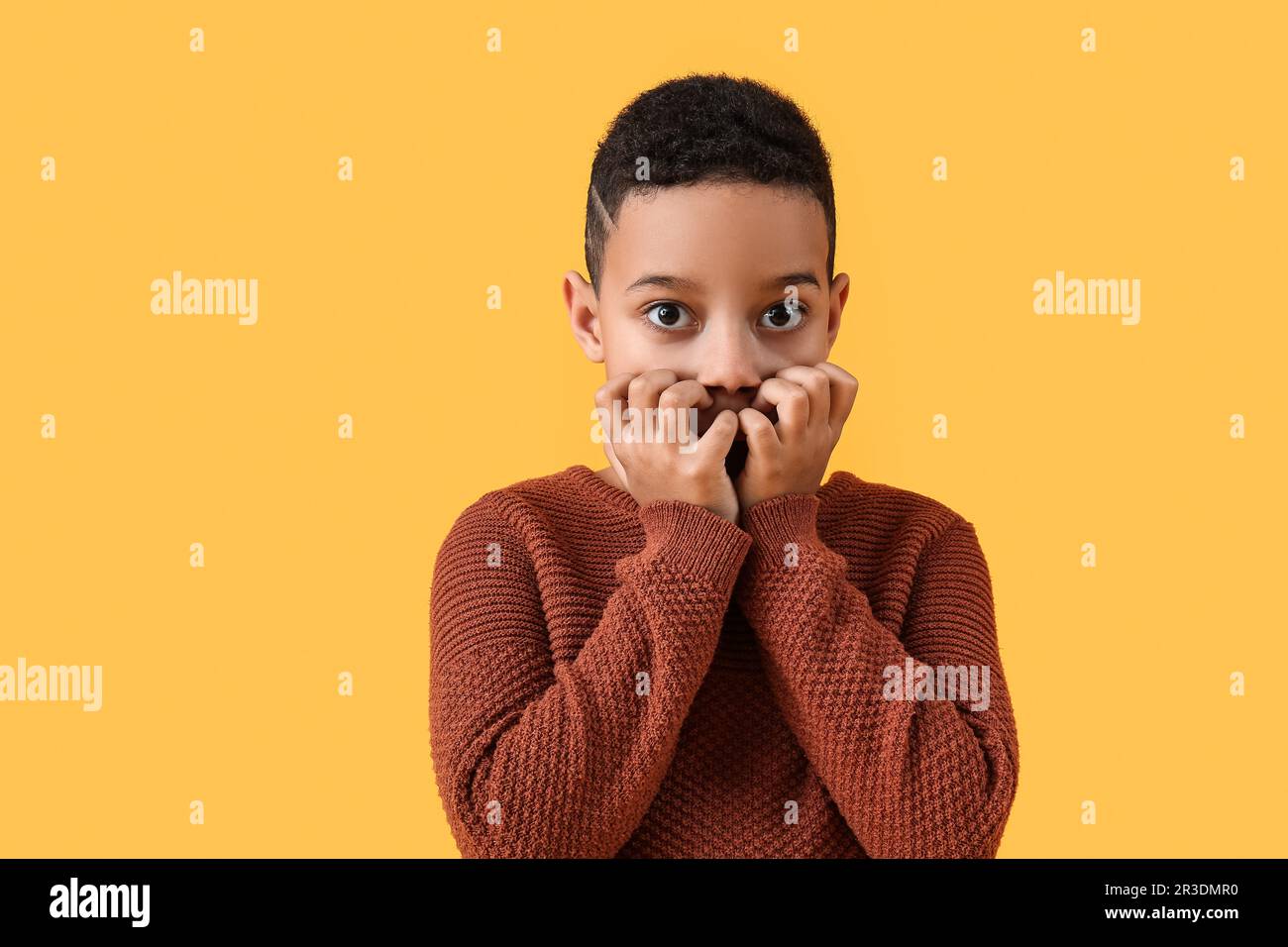 Scared little African-American boy on yellow background Stock Photo - Alamy