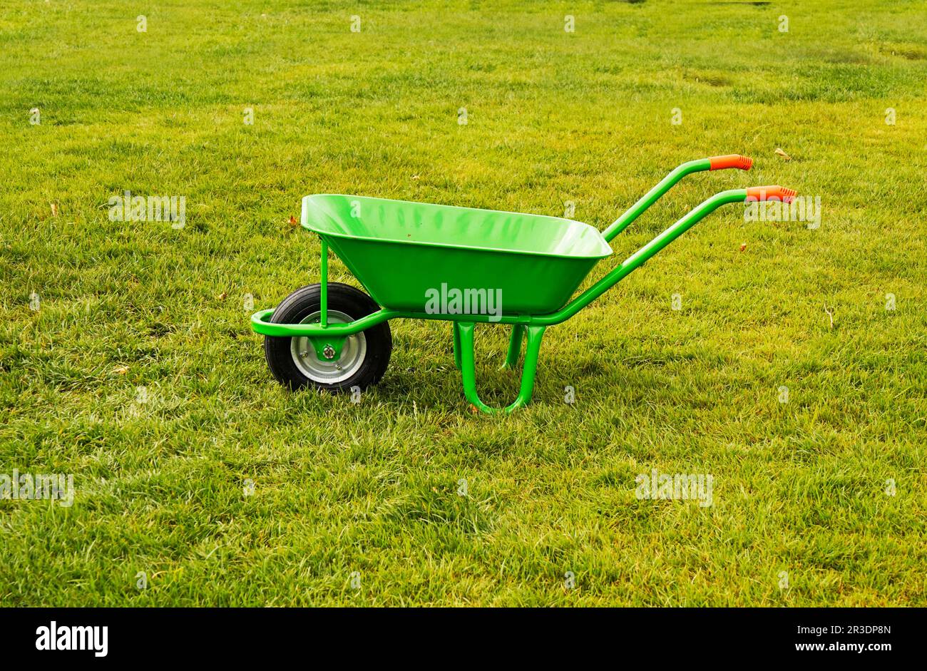 A green iron empty trash cart stands on the green grass,city services ...