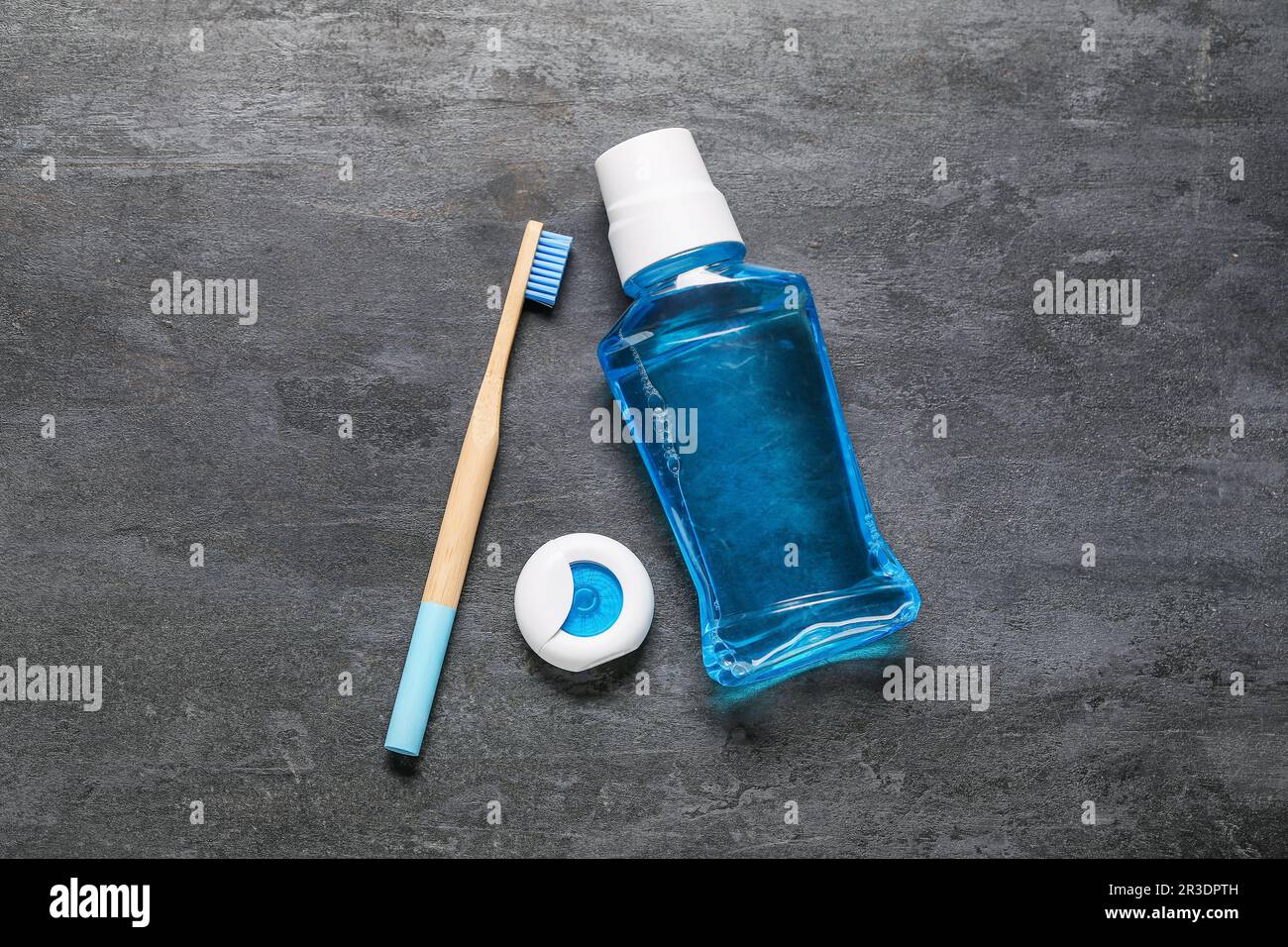 Dental floss with blue bamboo toothbrush and mouthwash on black grunge ...
