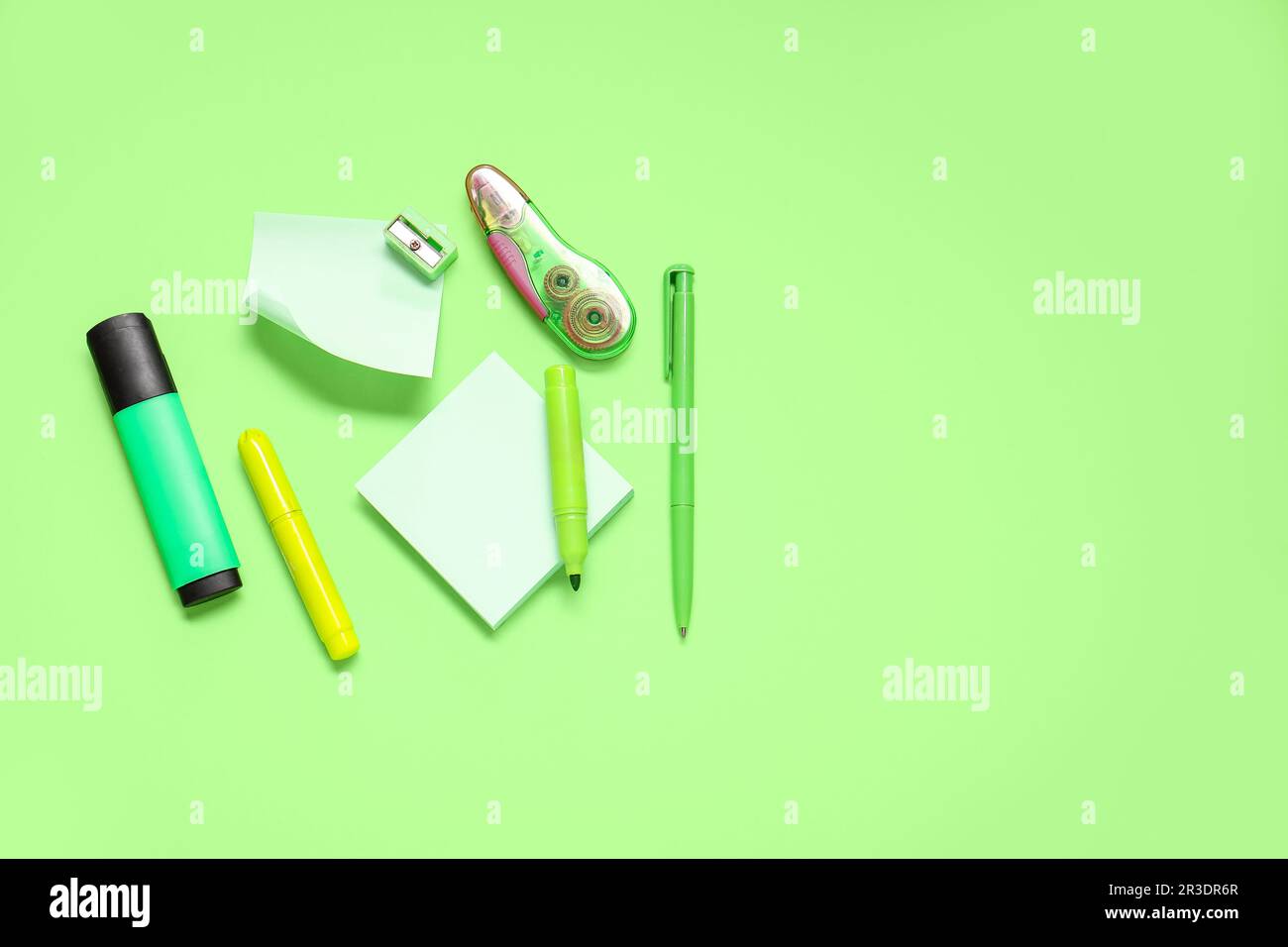 Sticky notes with different stationery supplies on green background ...