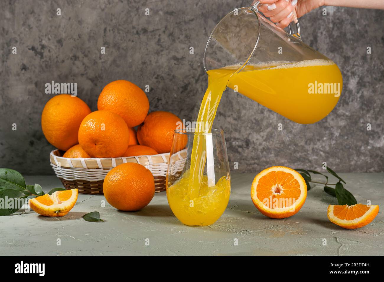 Woman pouring fresh orange juice from jug into glass on grey background Stock Photo - Alamy
