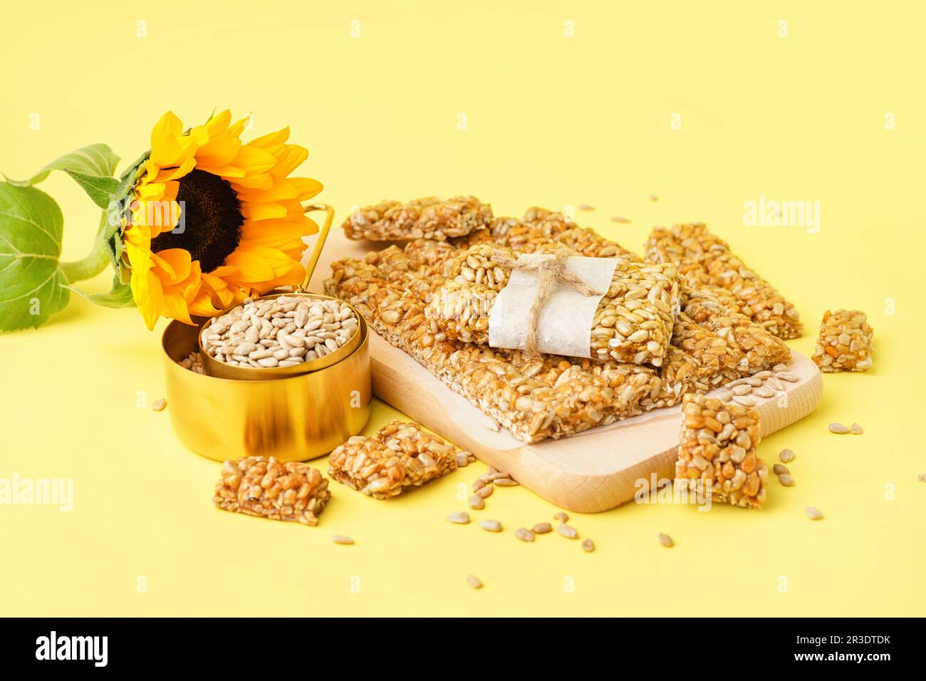 Measuring cups with tasty kozinaki and seeds on pale yellow background ...