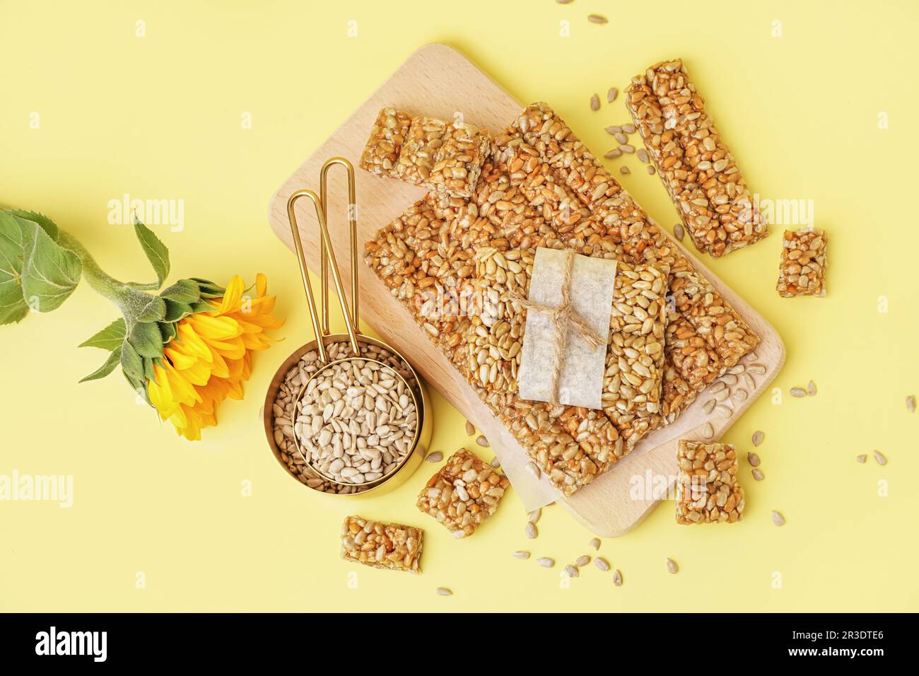 Measuring cups with tasty kozinaki and seeds on pale yellow background ...