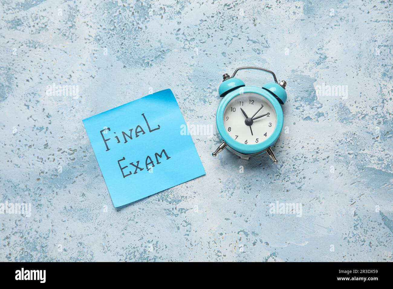 Sticky note with text FINAL EXAM and mini alarm clock on grunge blue ...