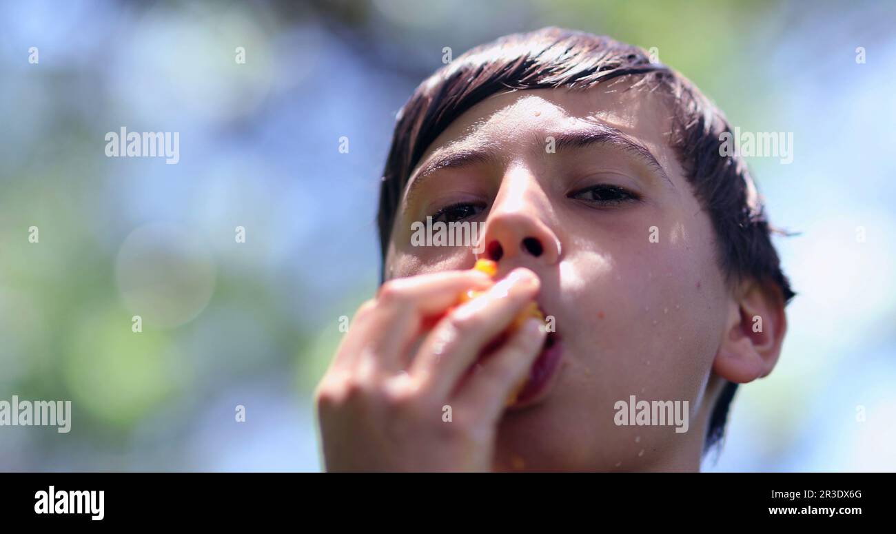 Kid eating peach outside. Child boy taking a bite of healthy fruit ...