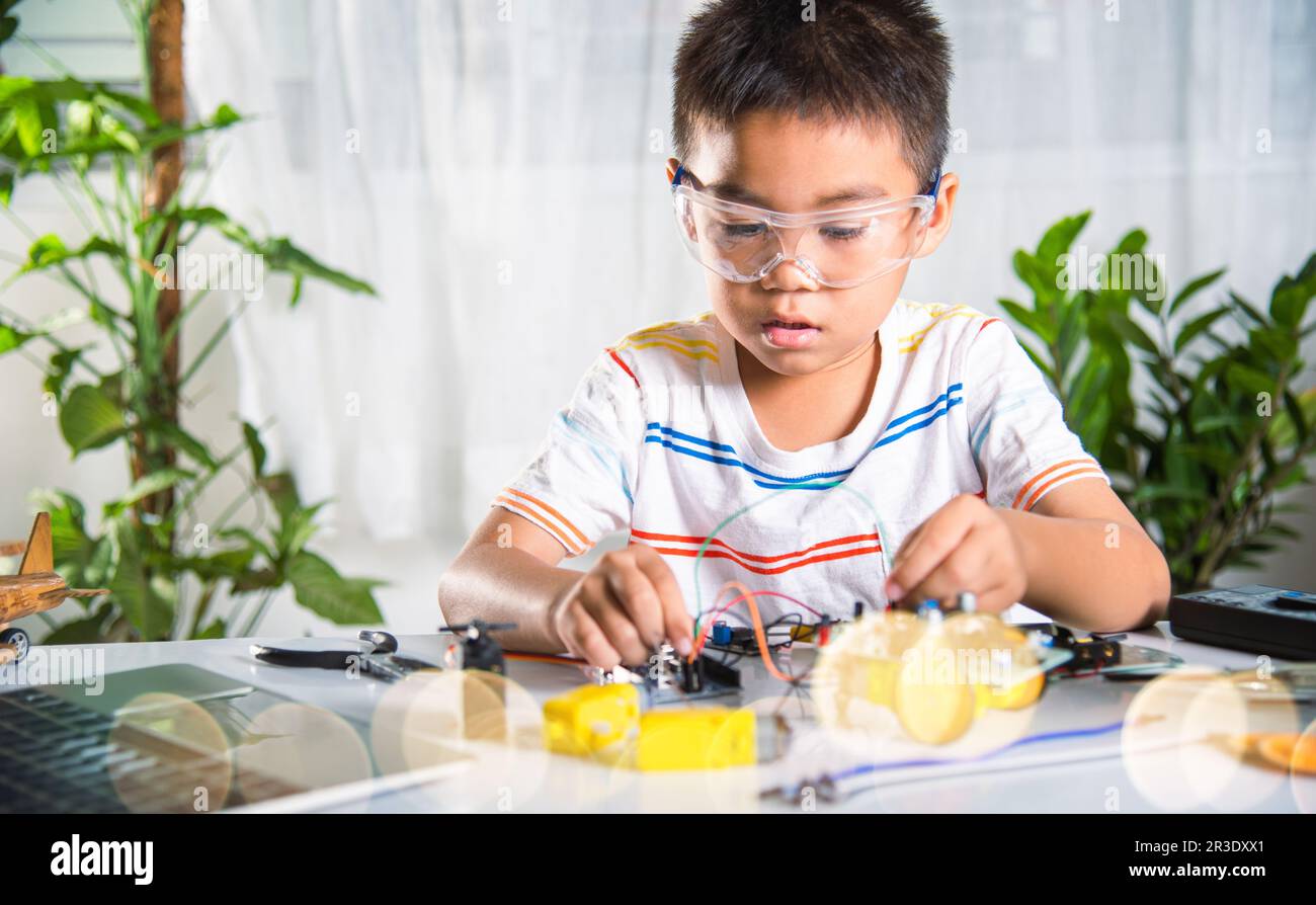 Asian kid boy plugging energy and signal cable to sensor chip with ...