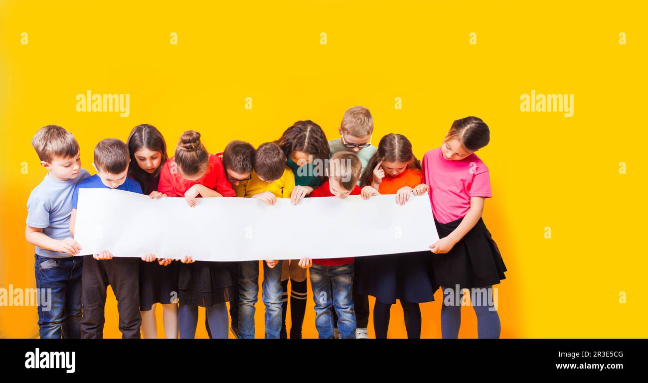 The group of kids holding a big white copy space poster Stock Photo - Alamy