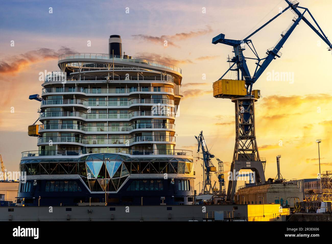 Scenic back view large modern luxury cruise ship liner under construction building cranes at dry ...