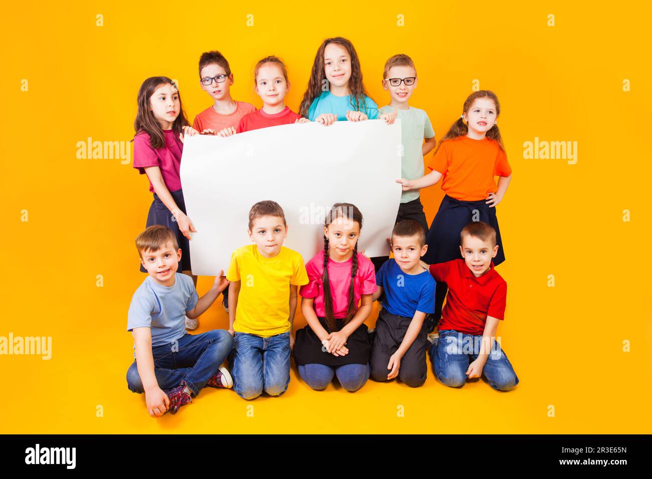 The group of kids holding a big white copy space poster Stock Photo - Alamy