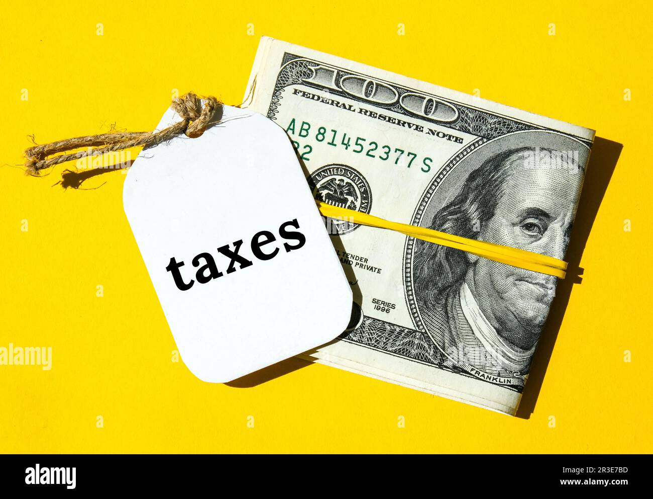 Paper note written word TAXES in black letters around Us Dollars ...