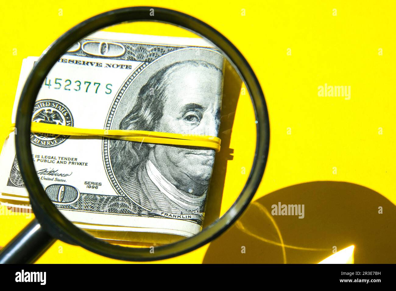 Magnifying glass on the background of a bundle of dollars close-up, one ...