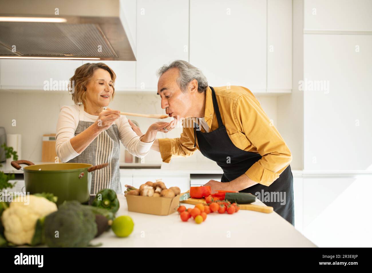 Cooking together concept. Senior woman feeding her husband while ...
