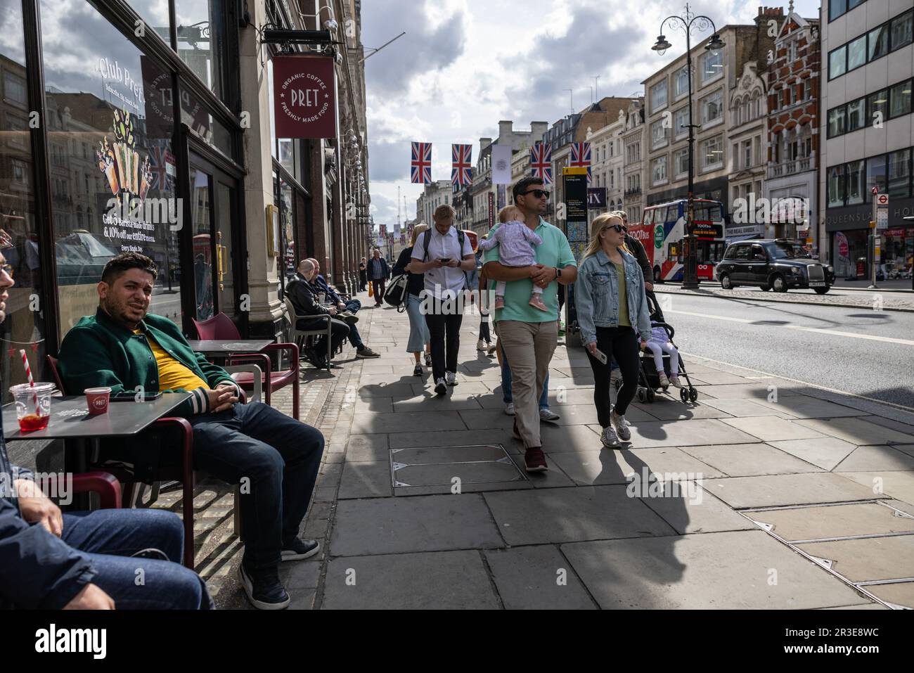 Tourists enjoy the sun alongside coffee drinkers sat outside a Pret A ...