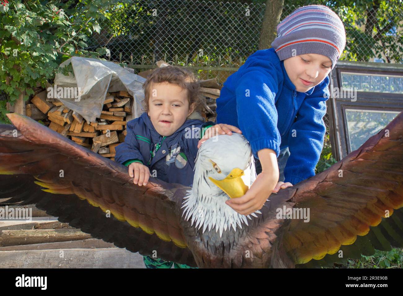 two brothers playing in the yard near the bird's eagle figurine Stock ...