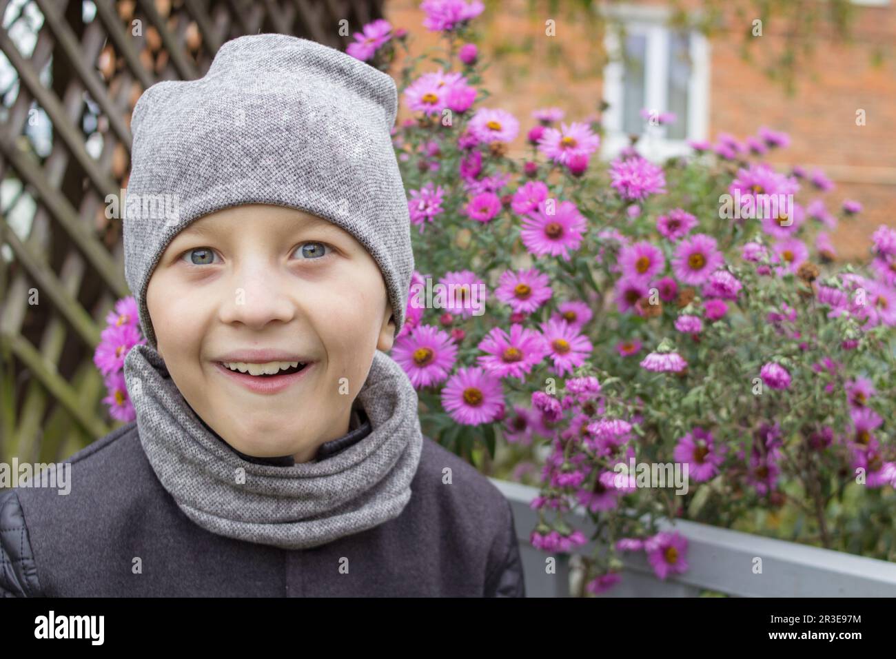 strange boy with a smile in a coat near flowers Stock Photo - Alamy