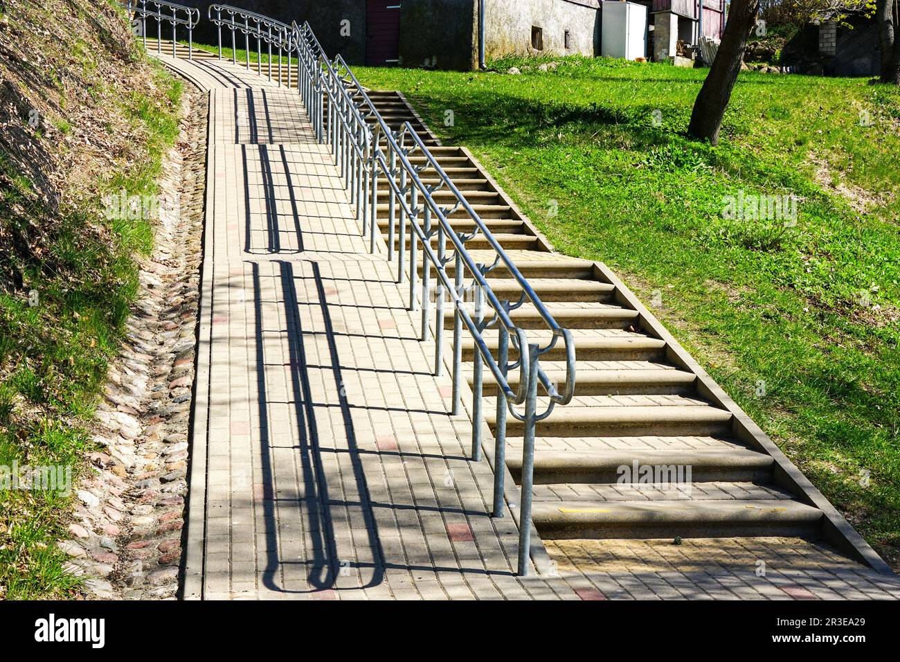 Outdoor paved stairs in hilly village with wheelchair lane and metallic ...