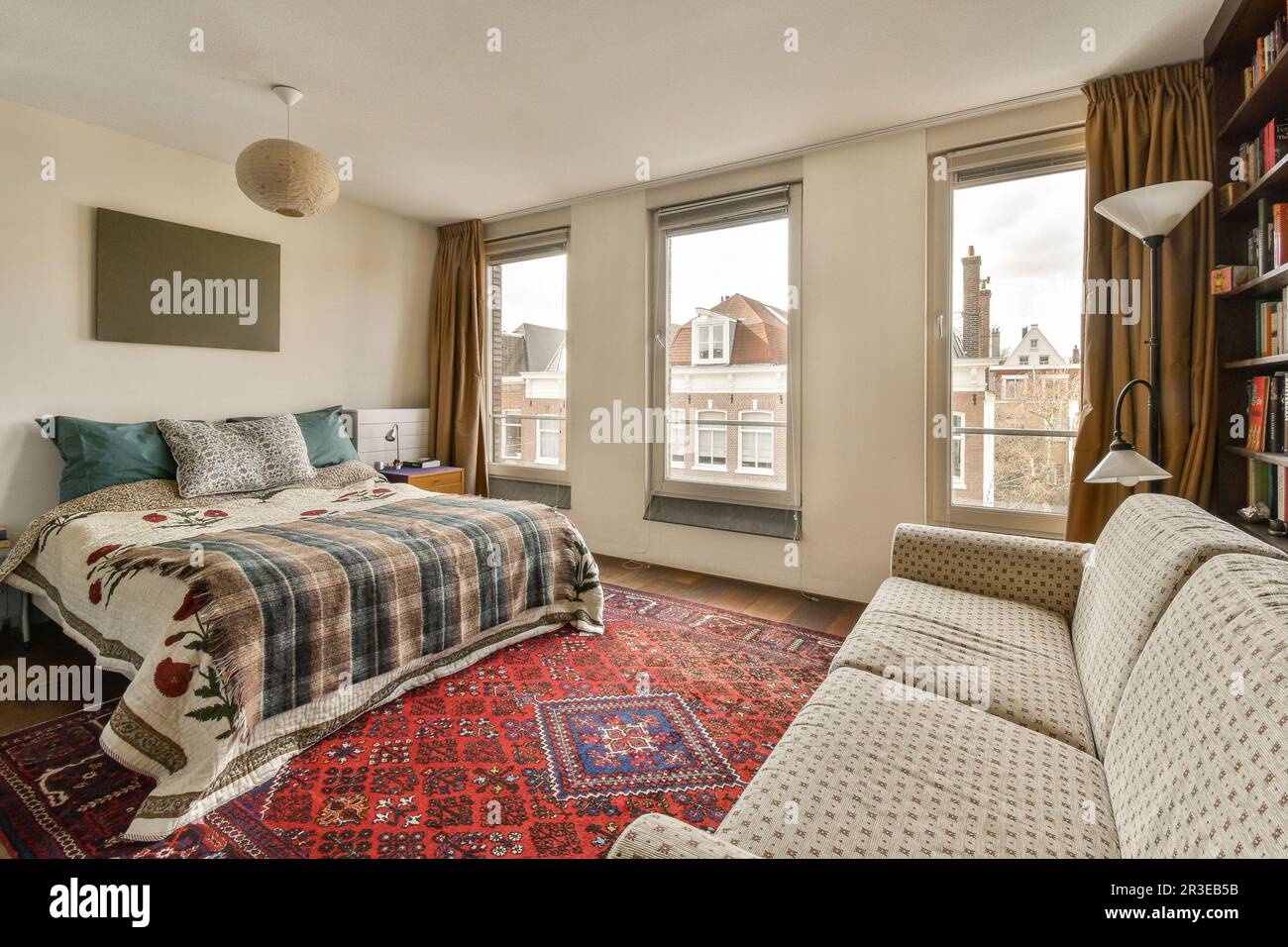 a living room with a bed, couch and bookcases on the floor in front of ...