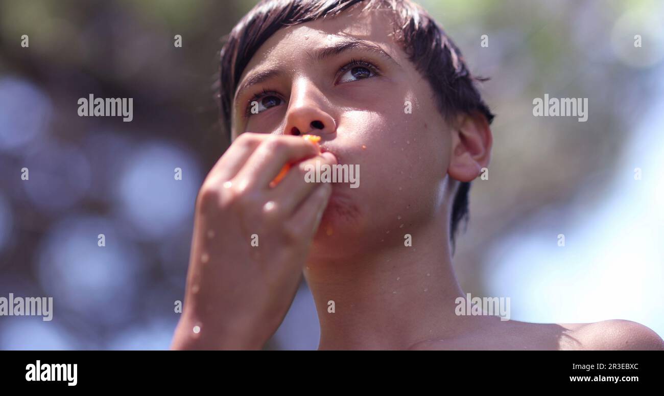 Pensive child eating fruit outdoors. Thoughtful kid chewing peach Stock ...