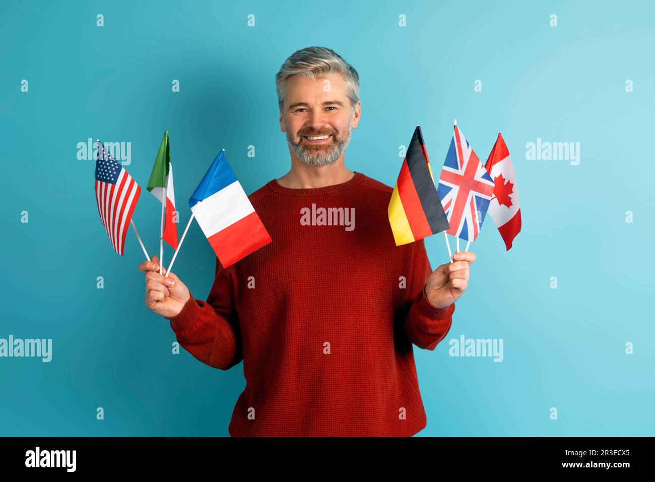 Emotional handsome middle aged man holding flags of diverse countries ...