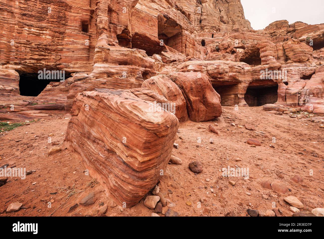 Simple dwelling ruins - cave like holes in stone wall, cloudy sky above ...