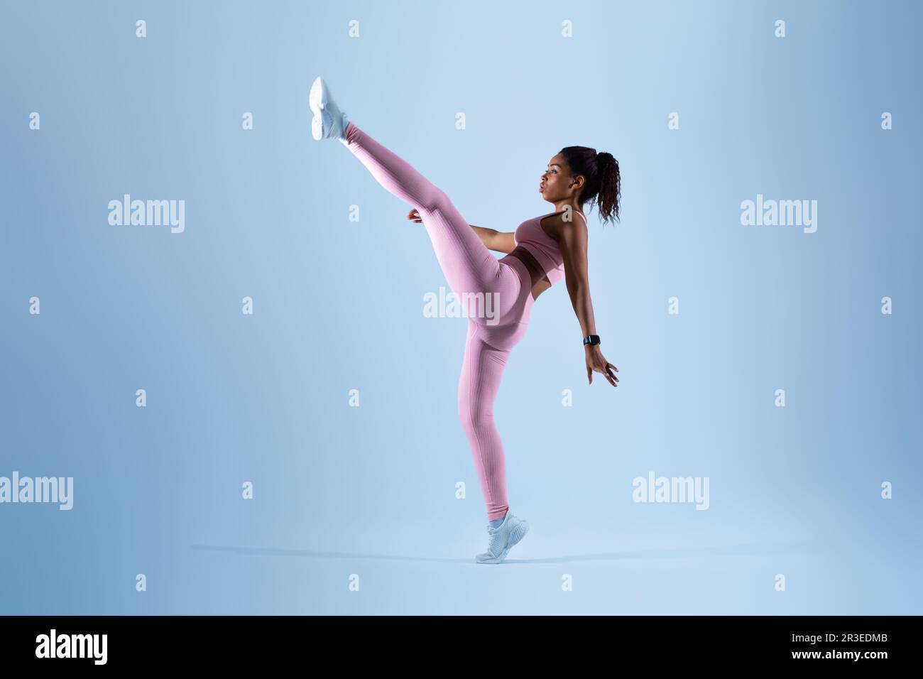 Motivated black lady doing karate kick move, raising leg and showing ...