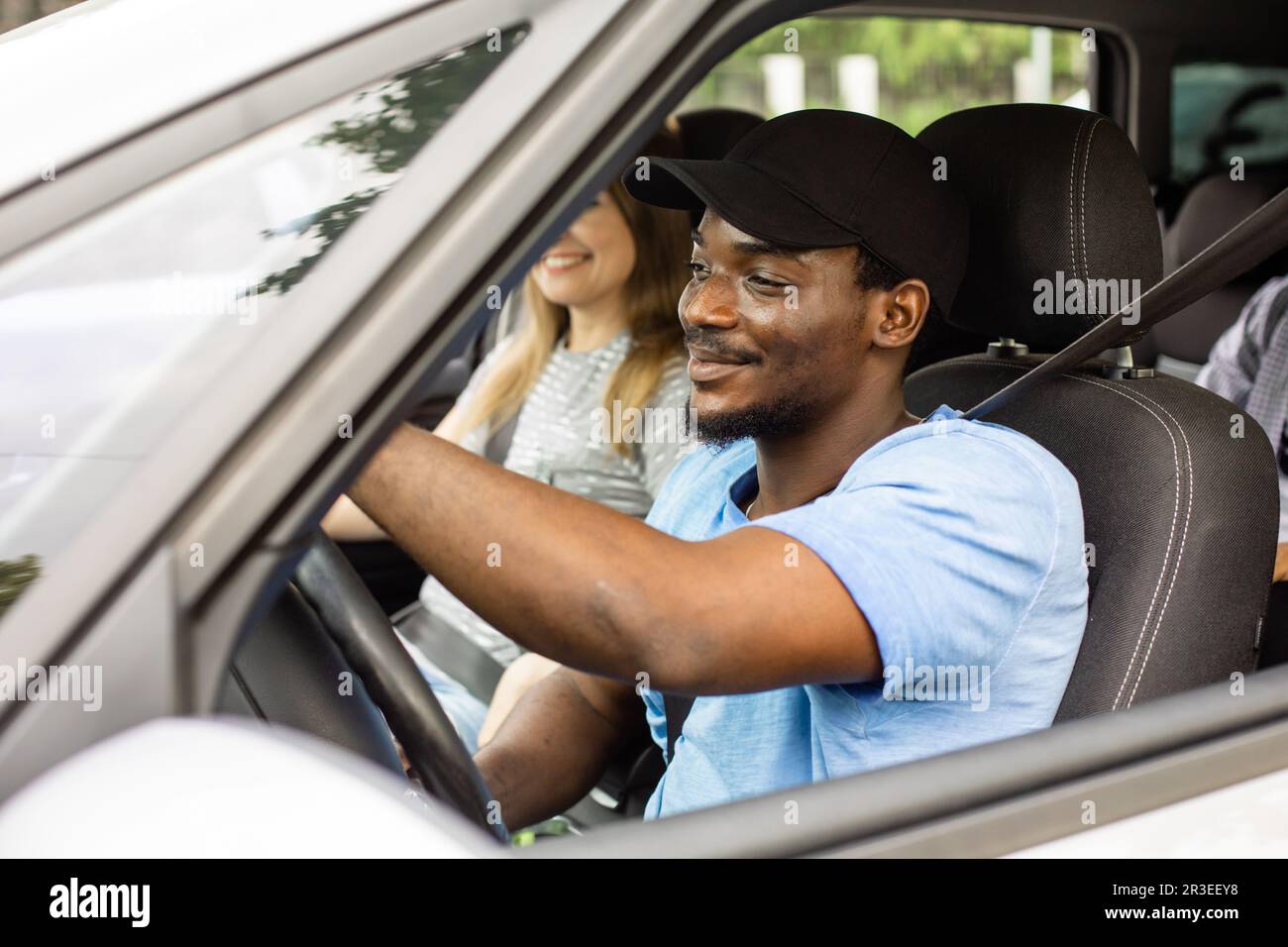 Cheerful young man driving car with friends on vacation Stock Photo - Alamy