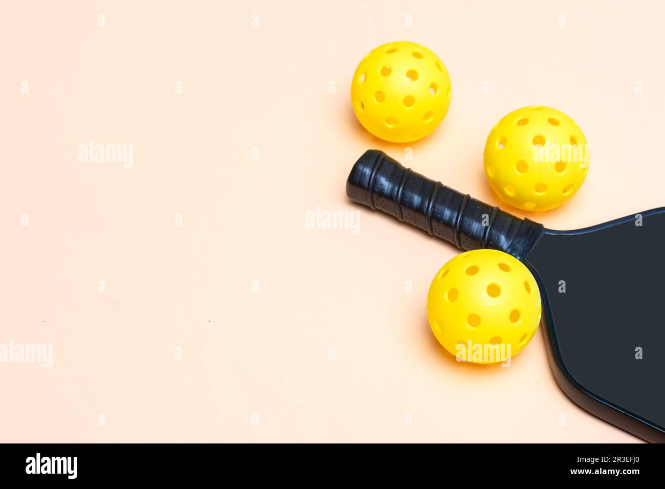 Black pickleball racket and ball on beige background. Horizontal ...