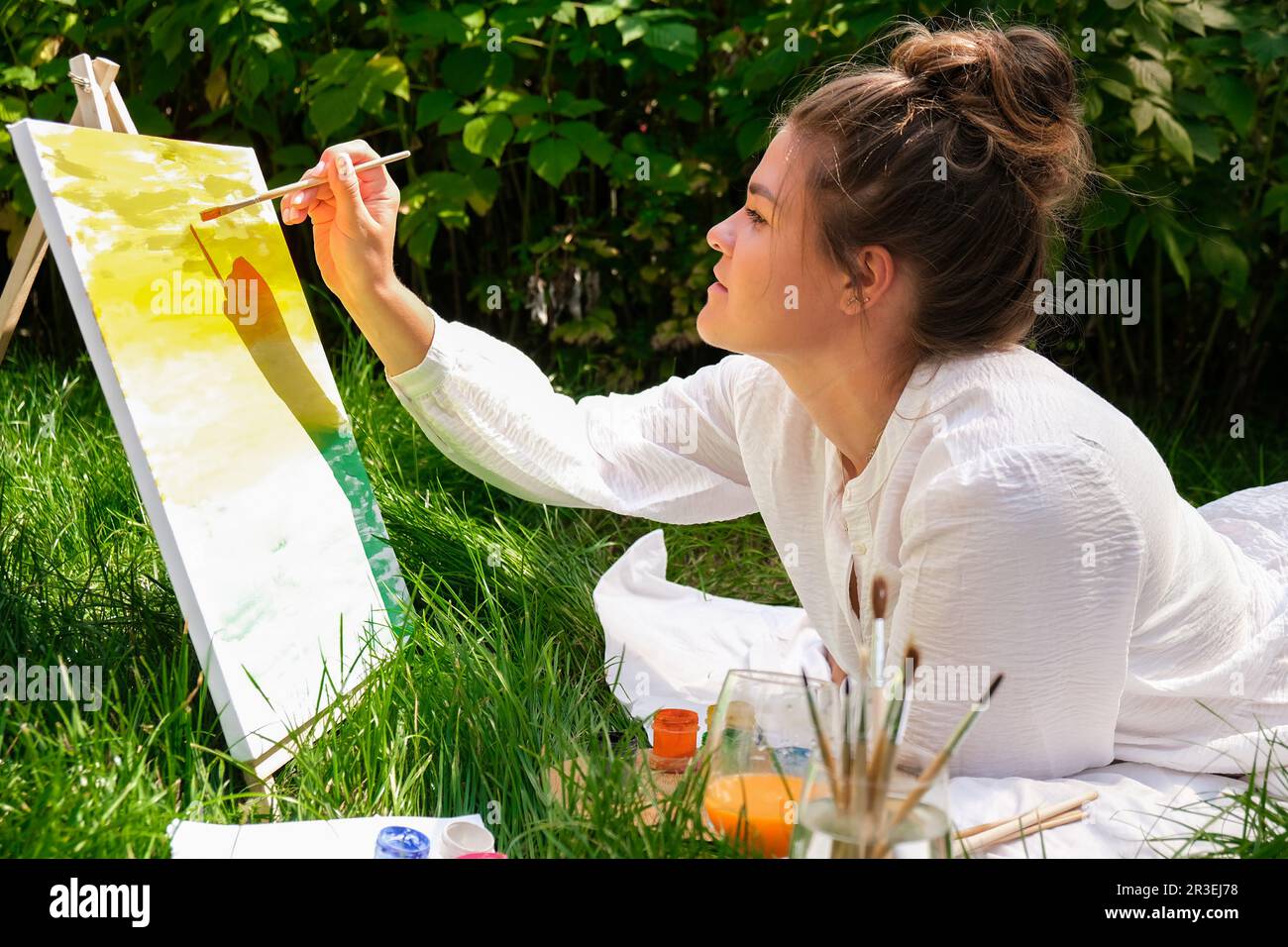 Artist painting on the easel outdoors in the garden. Open air outdoor art workshop. Draw on the ...