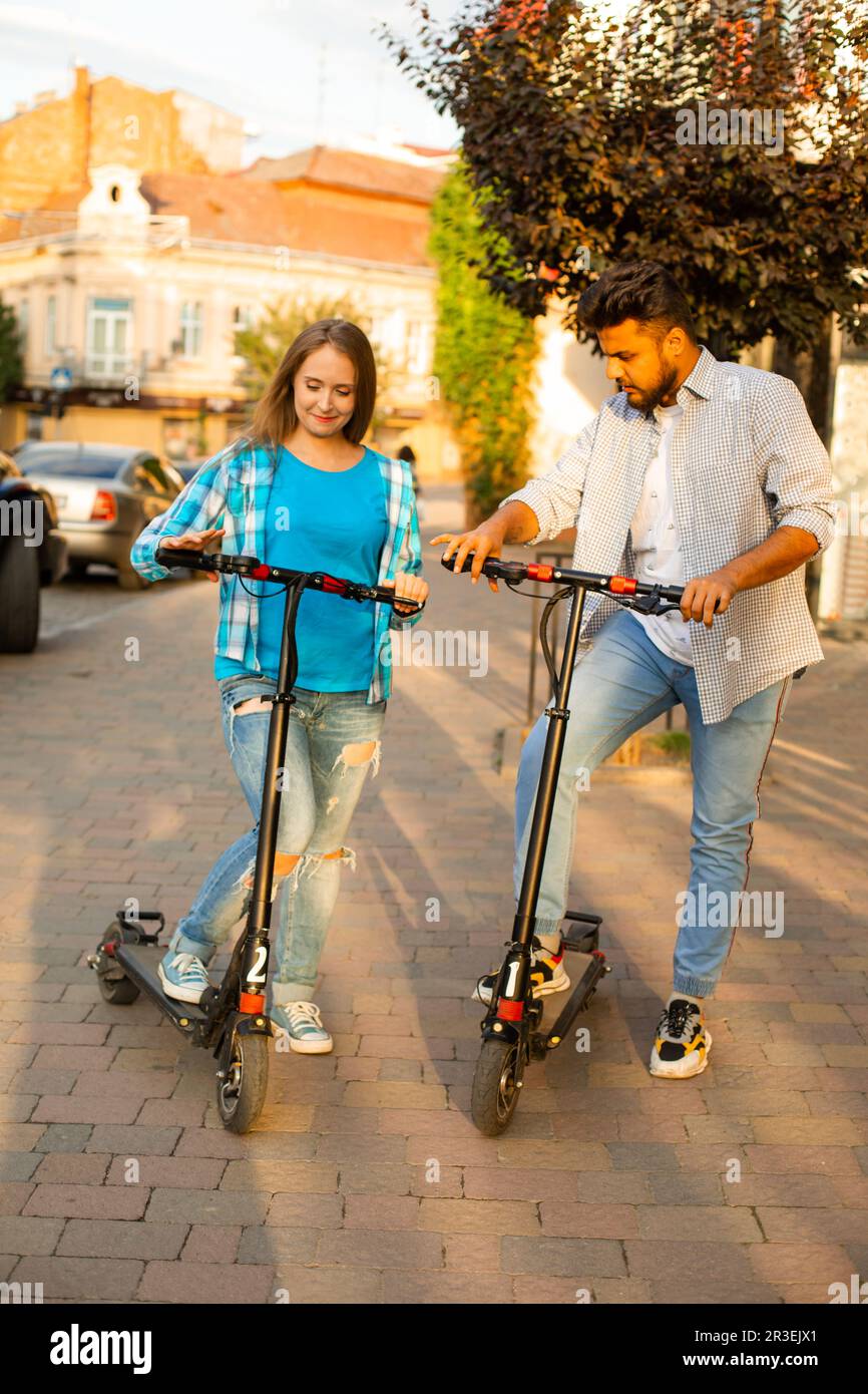 The loving couple ride an electric scooters and look at each other ...