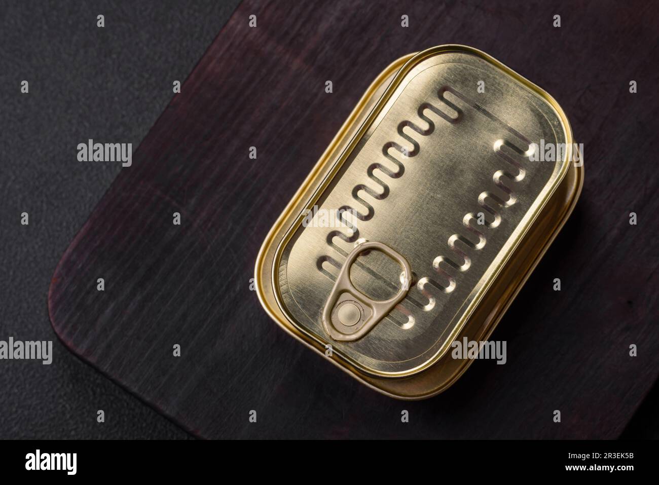 Tin or aluminum rectangular can of canned food with a key on a dark ...