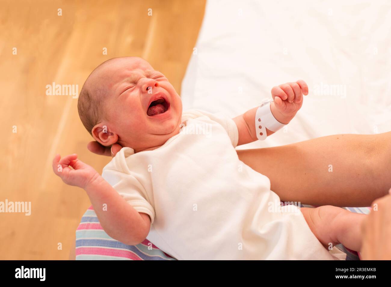 Mom holds her screaming baby in her arms Stock Photo - Alamy