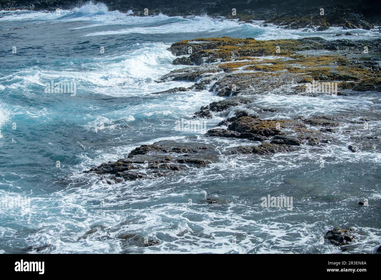 Cooled black lava beaten by the Atlantic ocean waves. View of sea waves ...