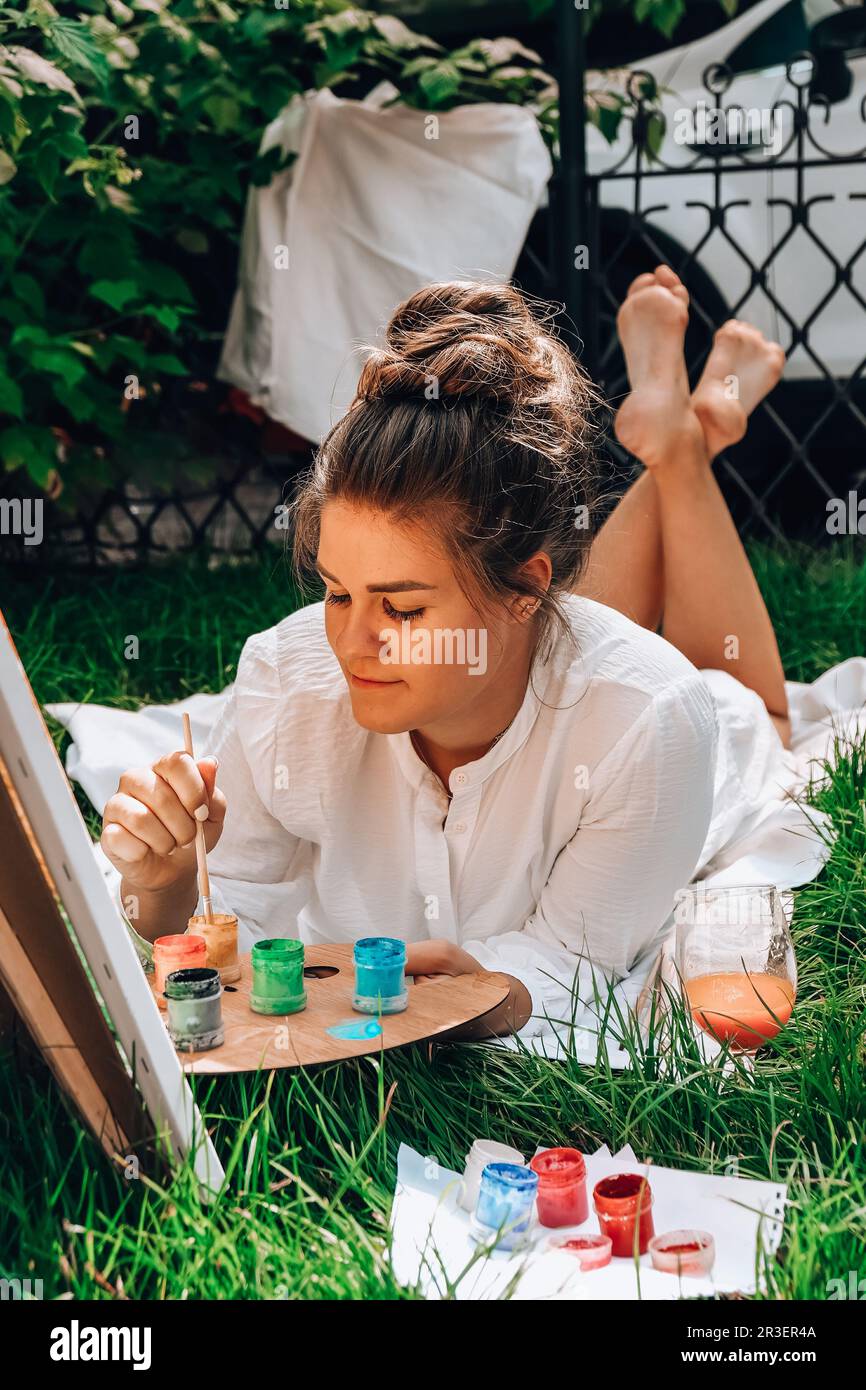 Artist painting on the easel outdoors in the garden. Open air outdoor ...