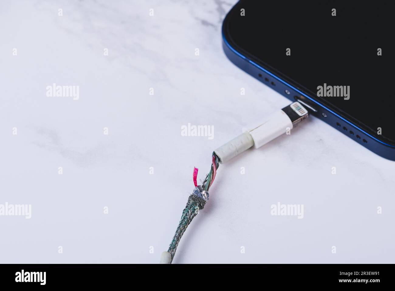 Top view of broken phone charger cable on the white table, visible wires Stock Photo - Alamy