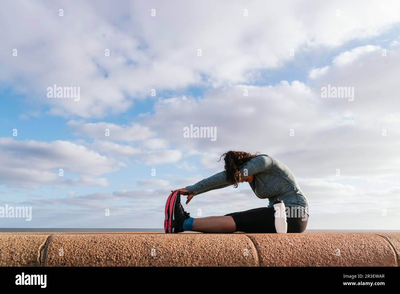 Woman sitting down stretching her legs Stock Photo - Alamy
