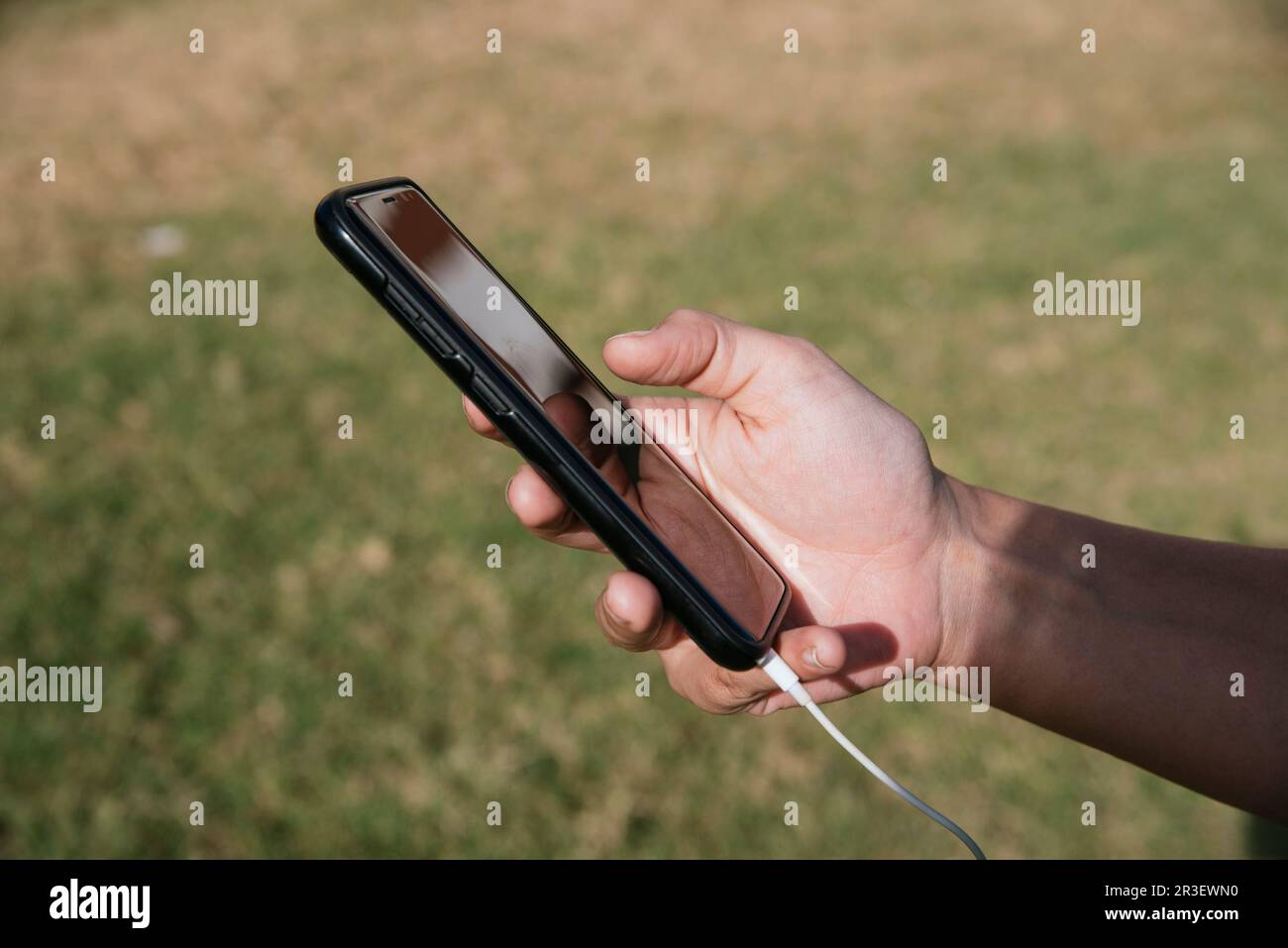 hand grabbing cellphone in the grass Stock Photo - Alamy