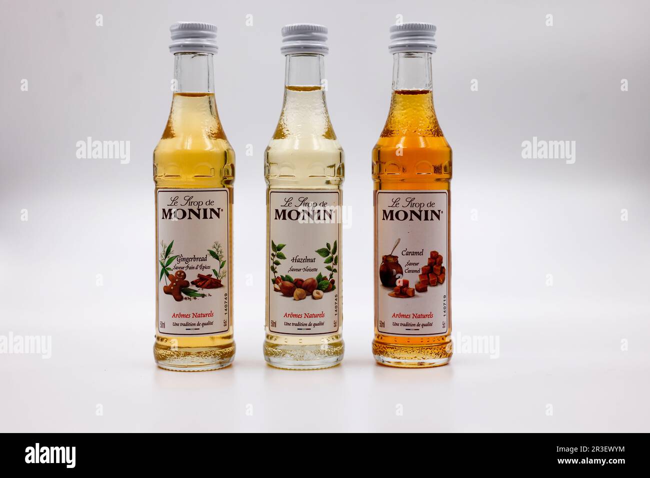Glass bottles of Monin flavored syrup or "sirop" isolated against white ...