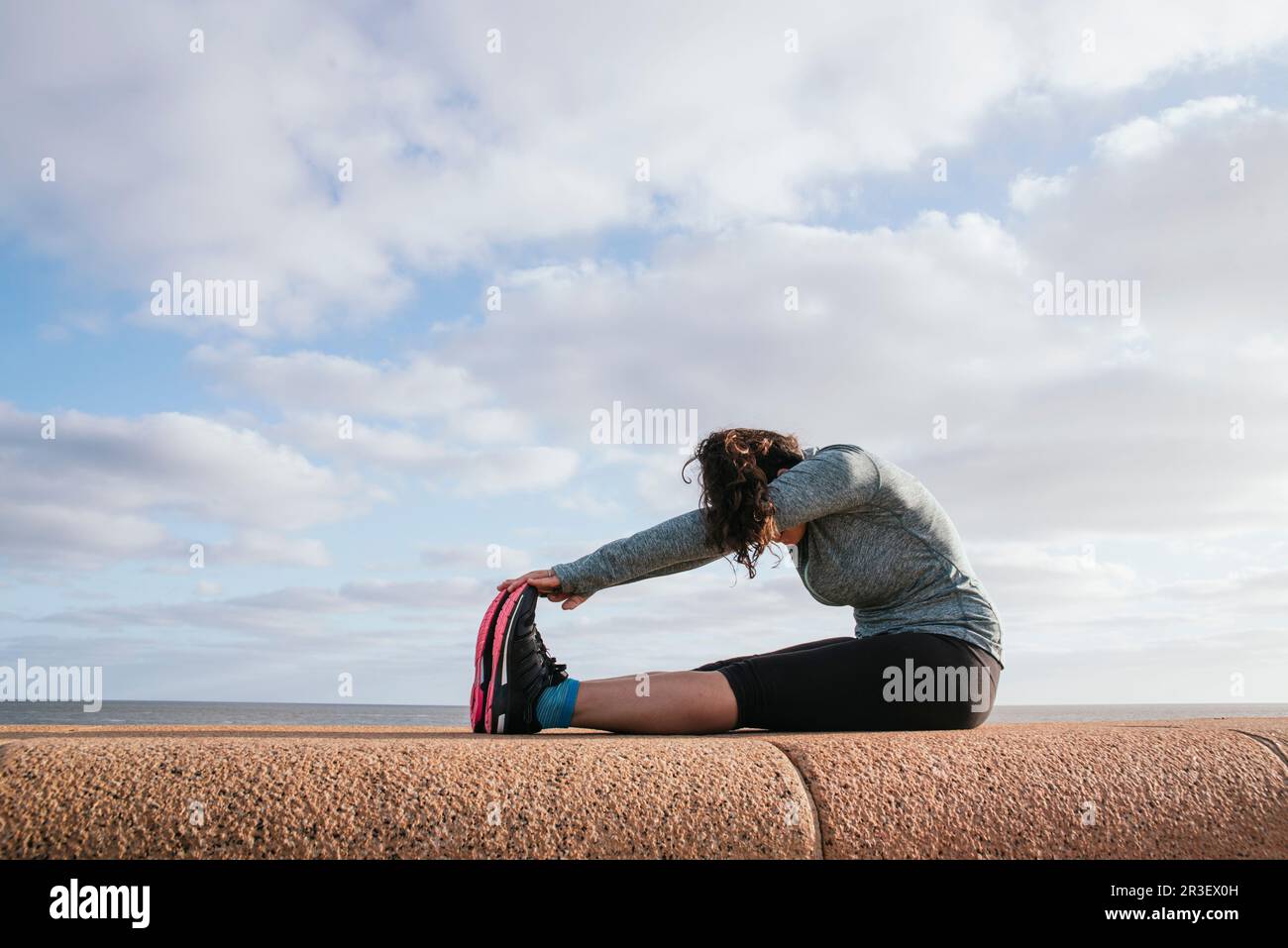 Woman sitting down stretching her legs Stock Photo - Alamy