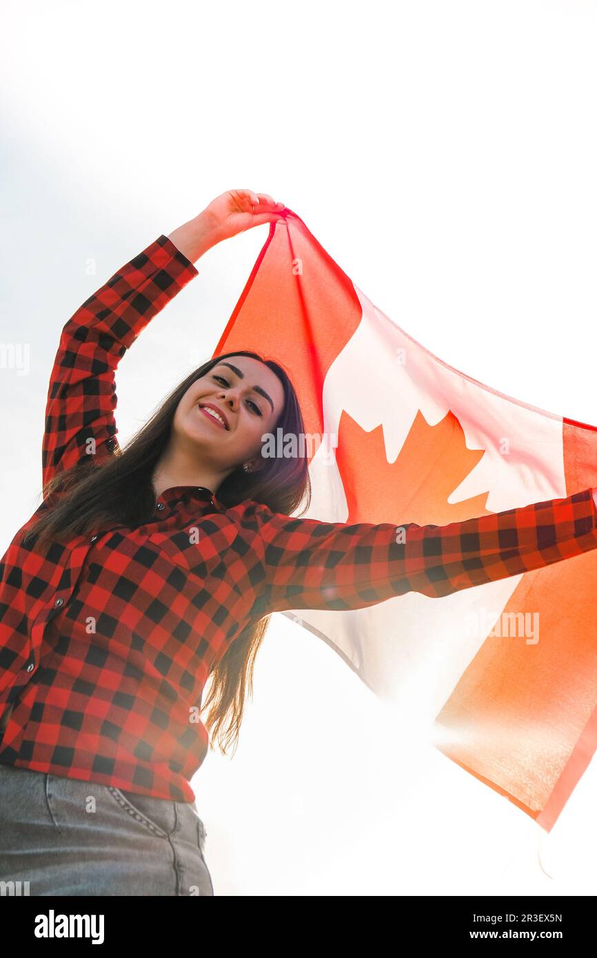 Young millennial brunette woman holding The National Flag of Canada ...