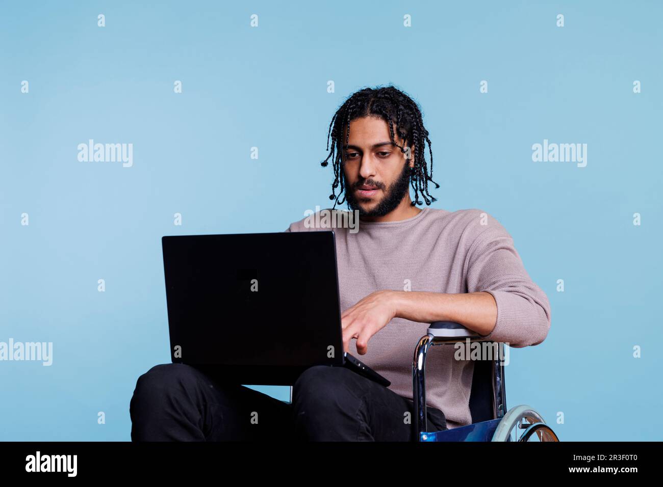 Arab man with physical impairment coding on laptop Stock Photo - Alamy