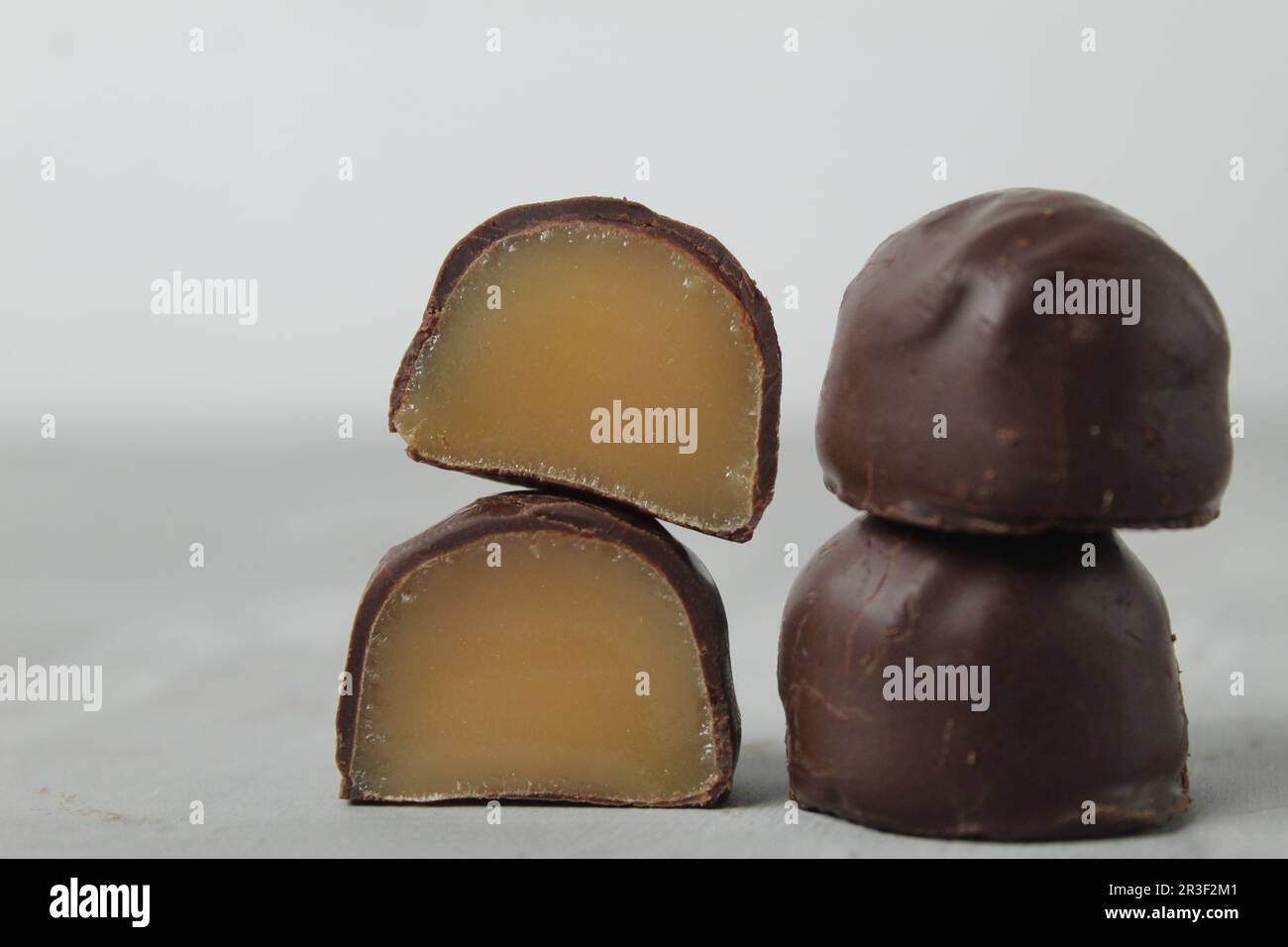 Chocolate body candies with cream ganache filling on a light gray ...
