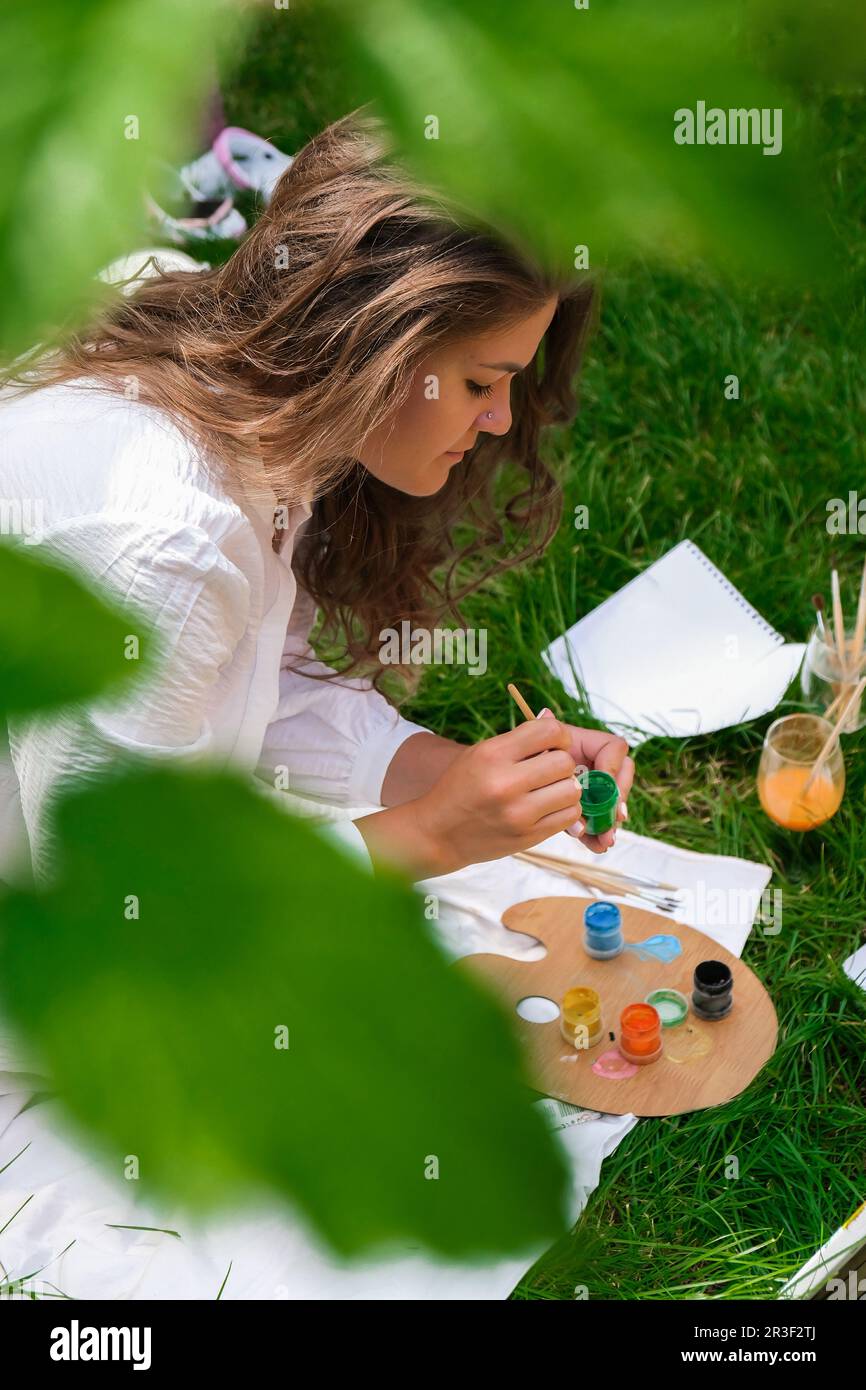 Artist painting on the easel outdoors in the garden. Open air outdoor ...