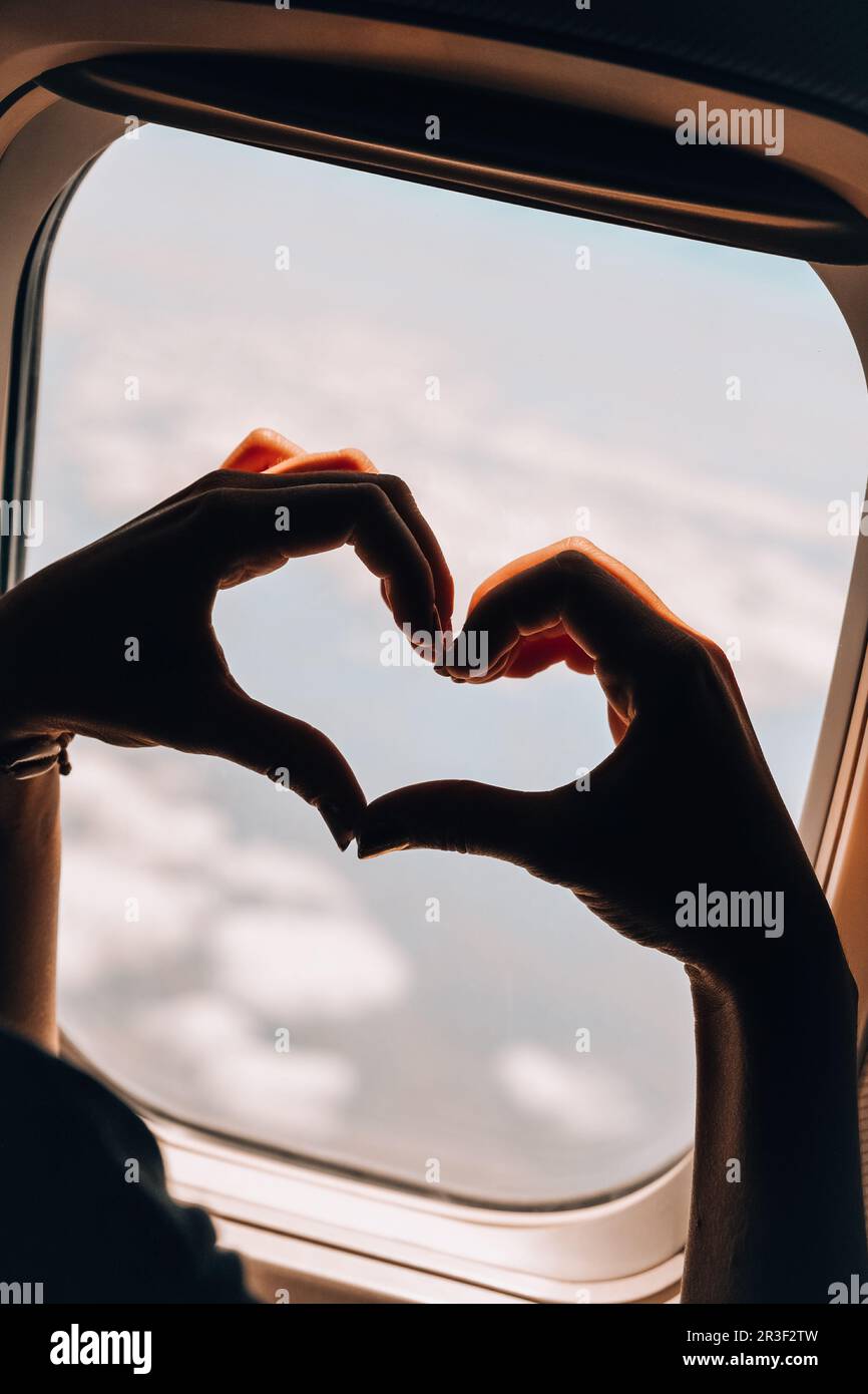 Female hand in heart shape View from the window of the plane. Airplane ...