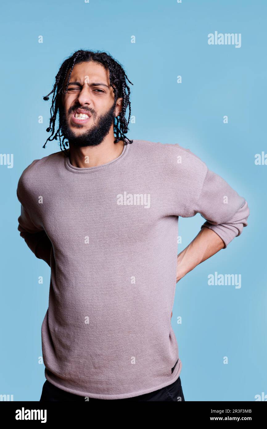 Arab man having lower backache with grimace on face Stock Photo - Alamy
