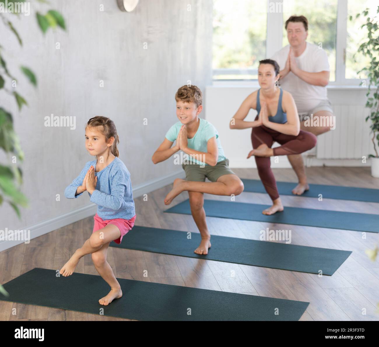 Little girl performs complex balancing asana standing on one leg and ...
