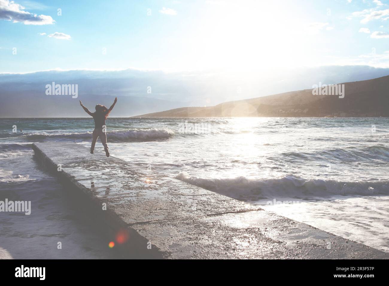 Feeling of freedom concept. Woman jump on pier facing to the sea with ...