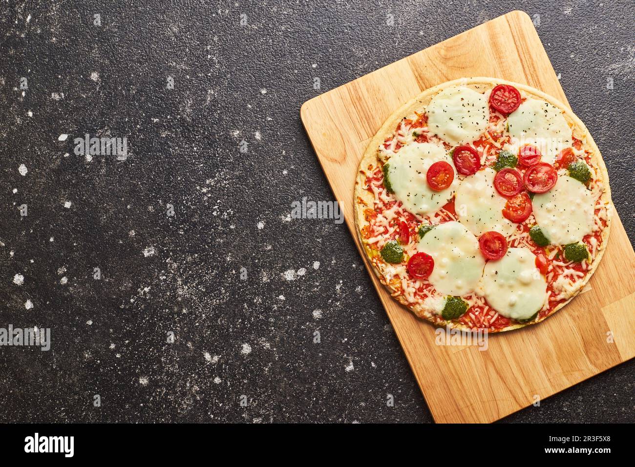 Fast food baked frozen pizza with cheese, tomatoes and pesto. Ready to ...