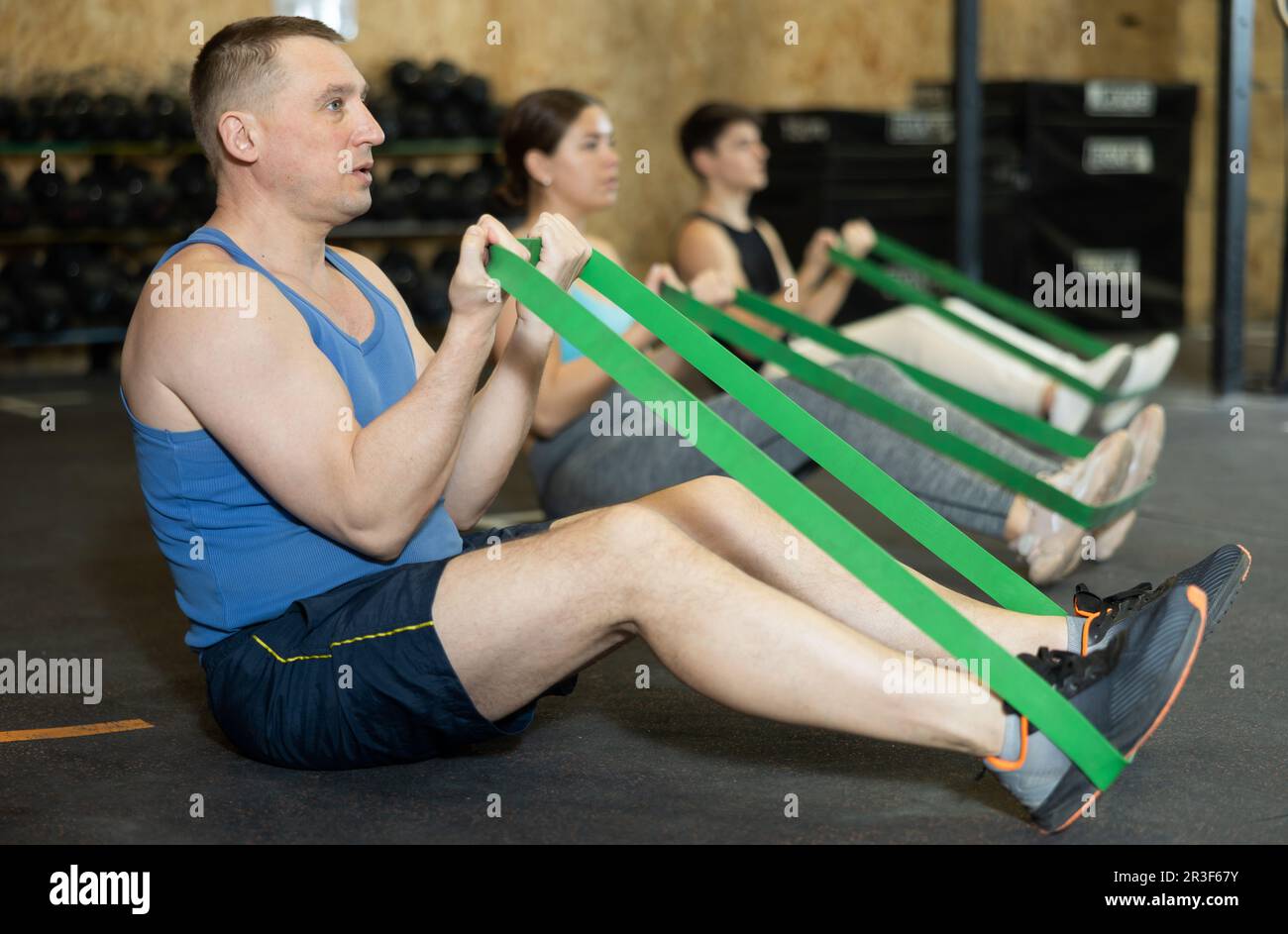 Active middle-aged man wearing sport clothes using resistance band ...